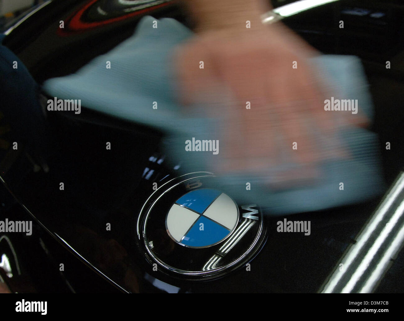 (dpa) - The picture shows a hand cleaning the hood of a black BMW 6 ...