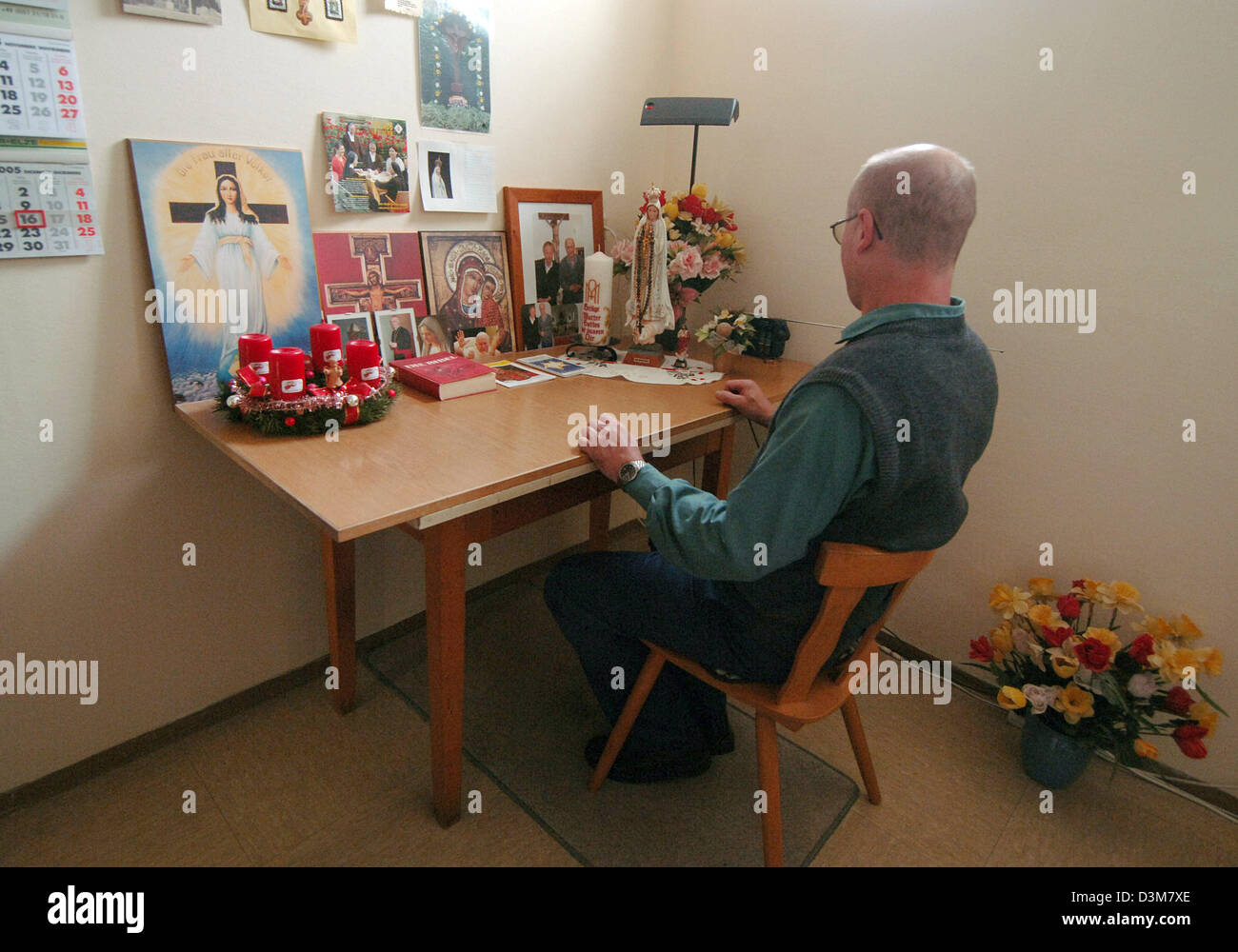 (dpa) - A prison inmate sits at his desk decorated with religious ...
