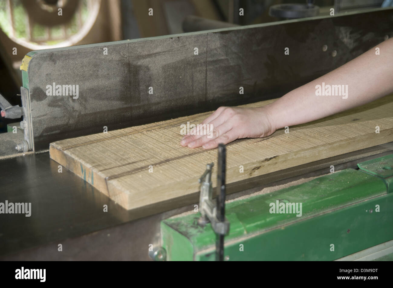 Female carpenter uses a powered carpenter's plane to flatten a plank of ...