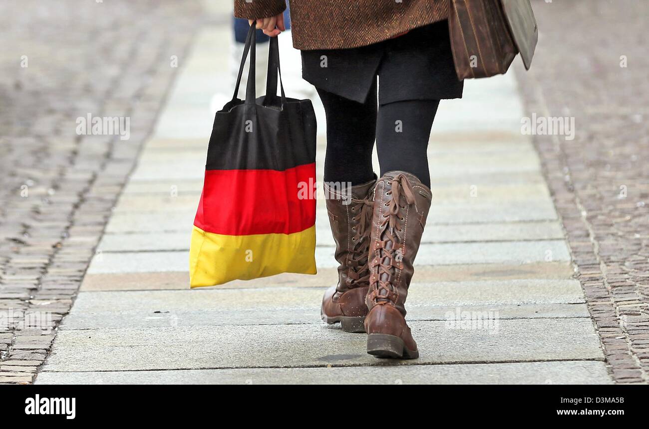 A woman with a shopping bag sporting the German national colours walks ...