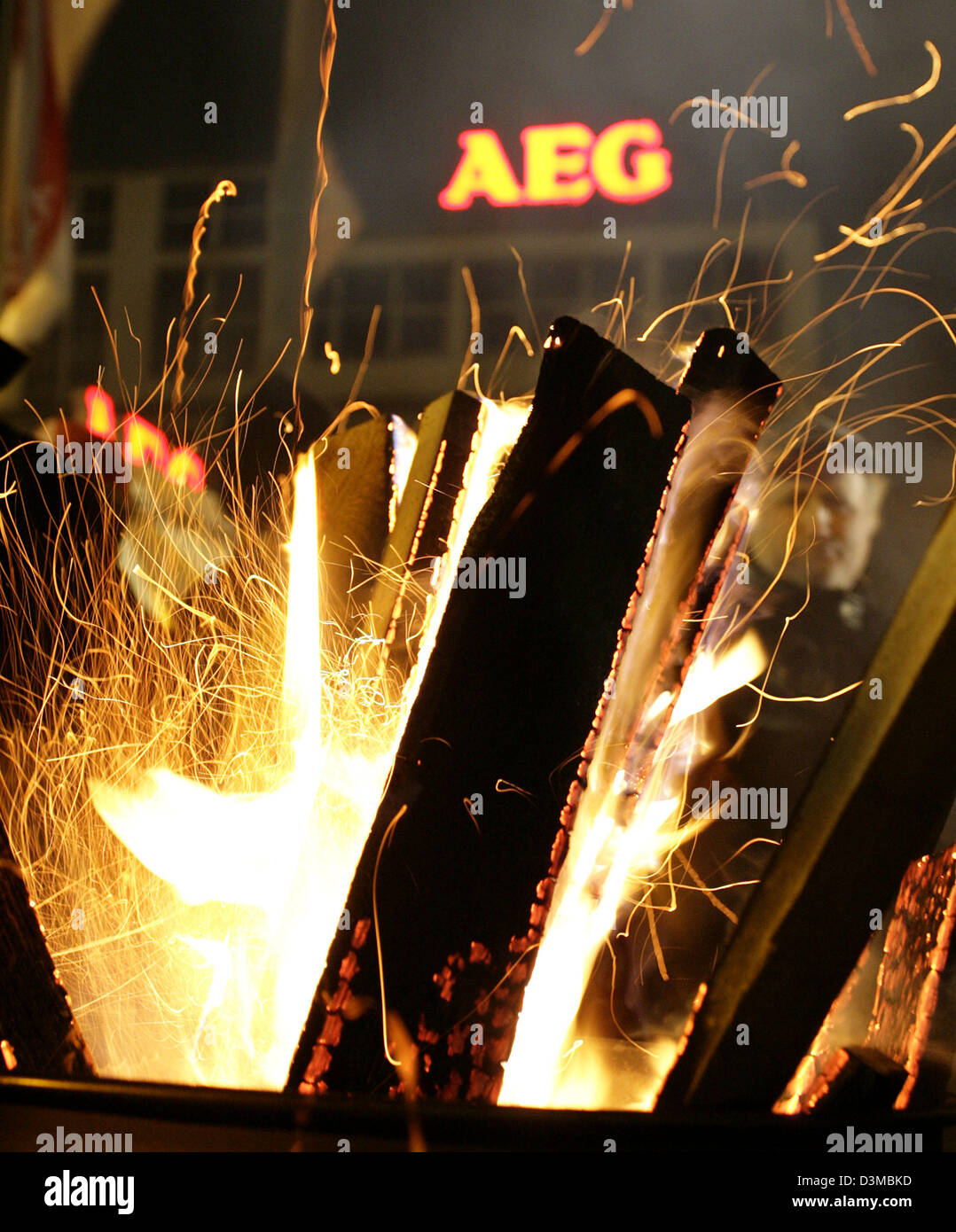 Logs of wood burn in a barrel in front of the factory gates of AEG ...
