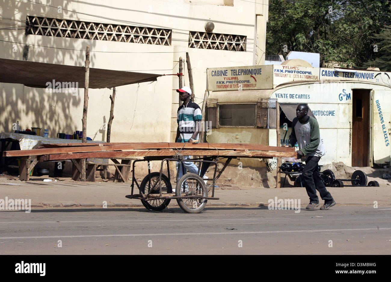 (dpa file) - A carpenter transports wooden poles on a rusty hand cart ...