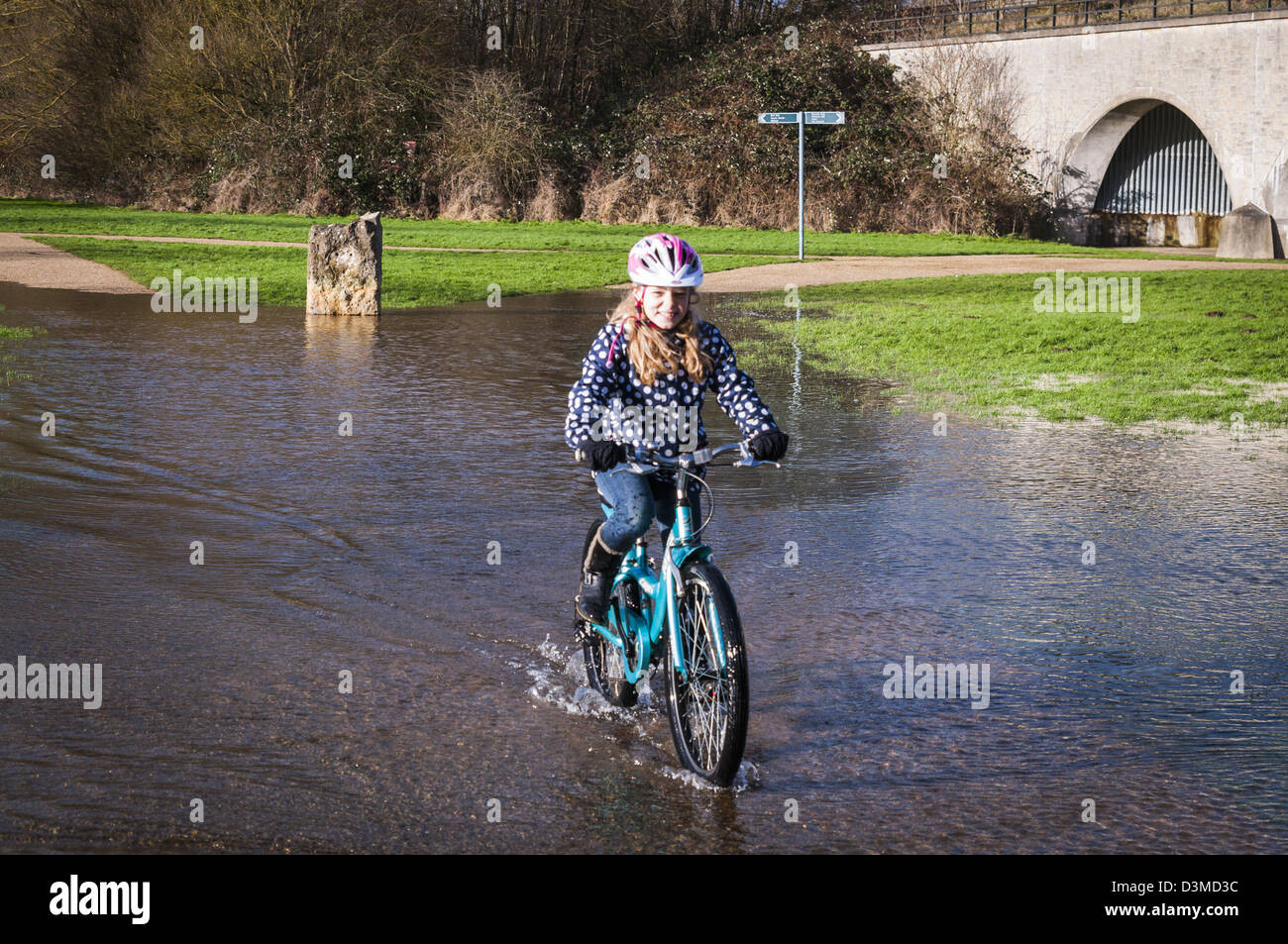 Girl cycling through water on a flooded footpath in Milton Keynes Stock ...