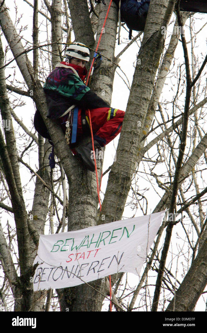 A conservationist sits on a tree with a protest banner at the terrain ...