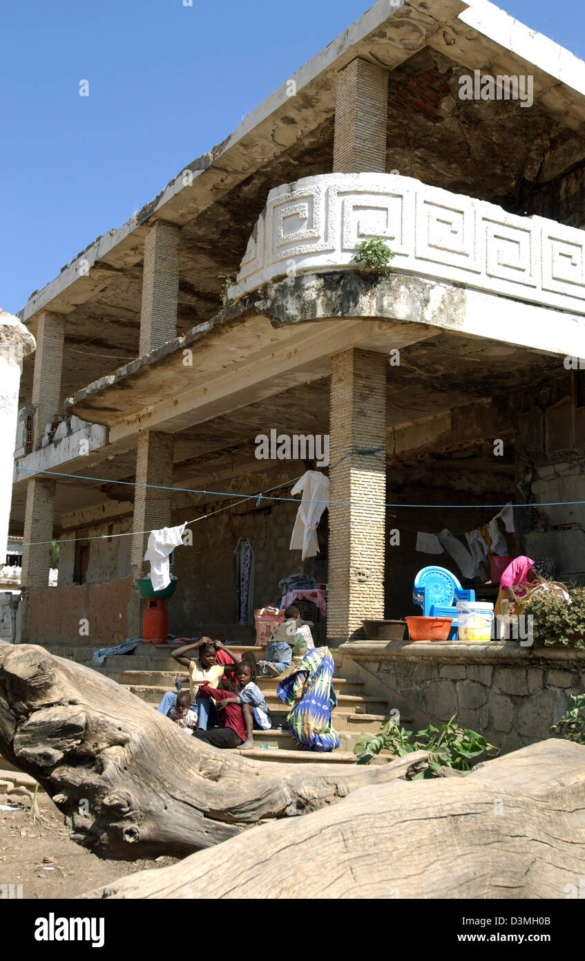 (dpa file) A small group of people sit in front of the destroyed house ...