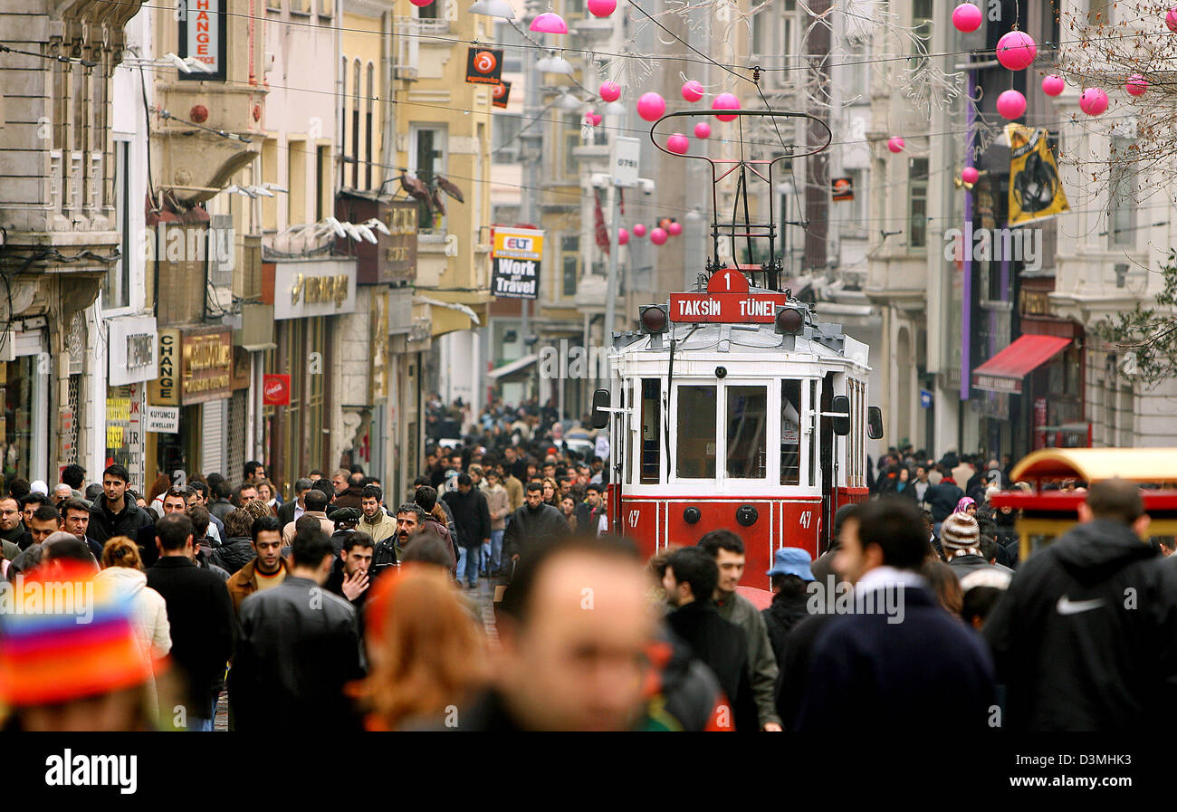 Crowds and a historic tram move through a busy street in downtown ...