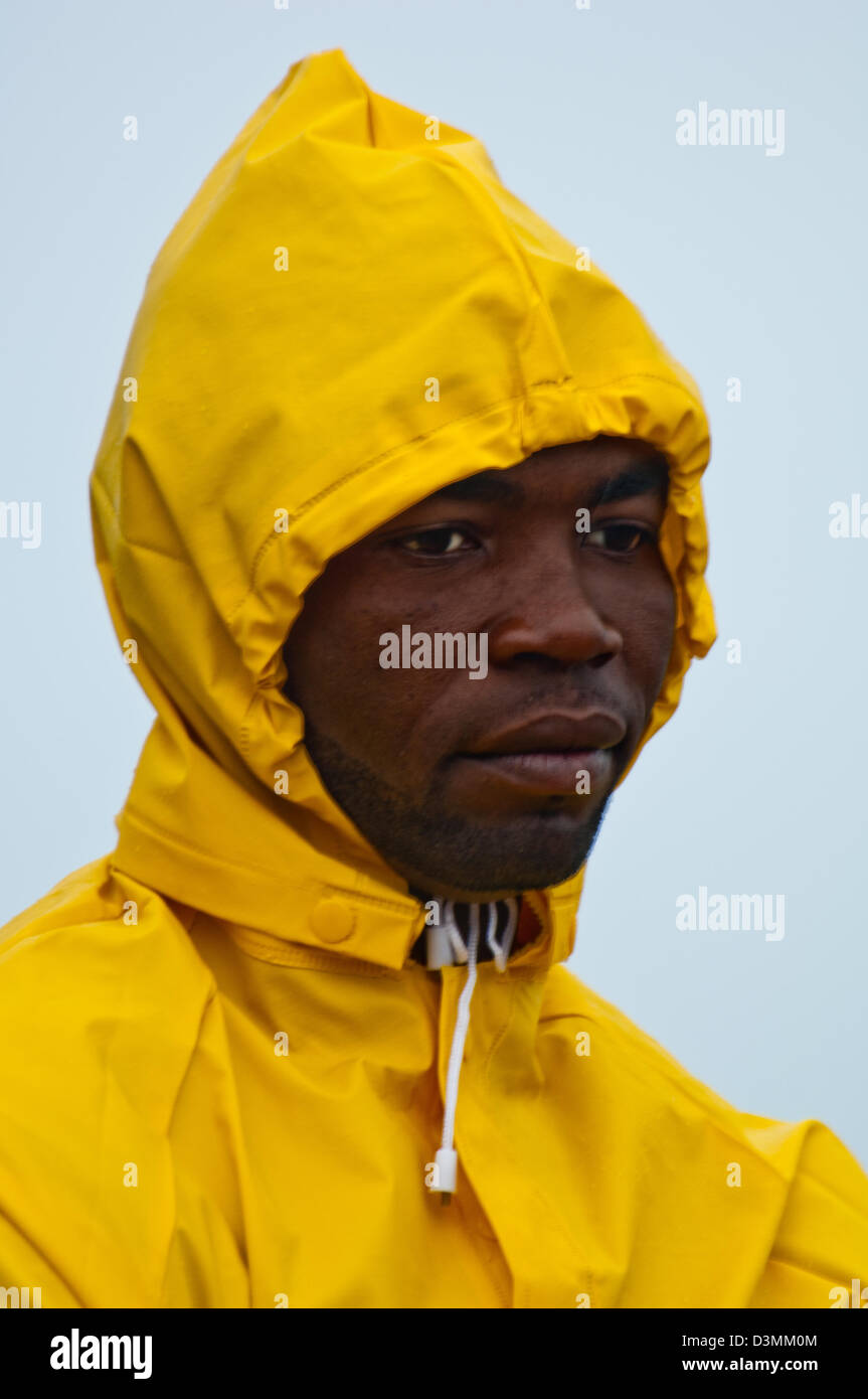 Bahamian boat captain wearing a hood and slicker on a rainy day, Andros ...