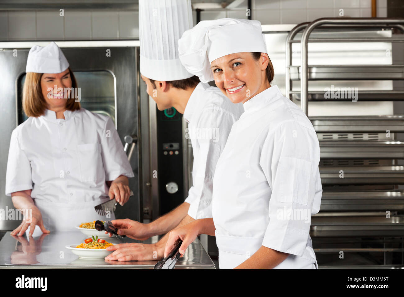 Female Chef With Colleagues In Commercial Kitchen Stock Photo - Alamy