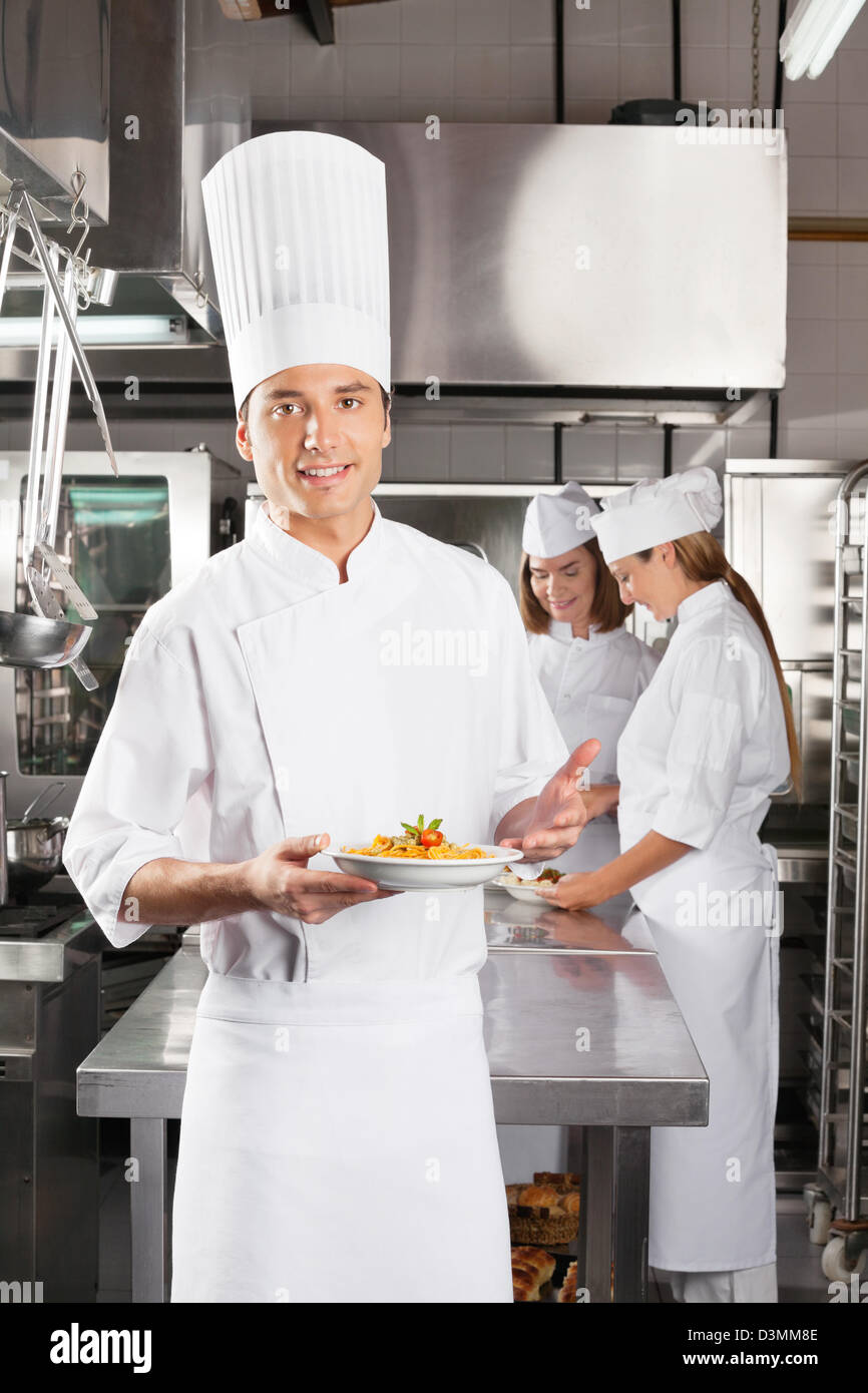 Confident Chef Presenting Dish In Commercial Kitchen Stock Photo - Alamy