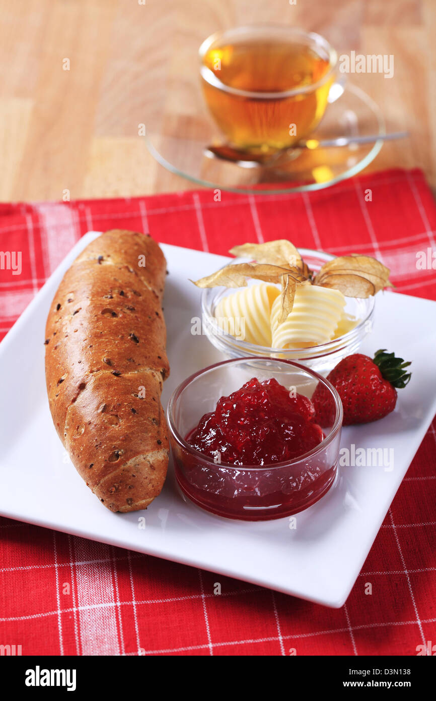 Breakfast of brown roll, butter and jam Stock Photo - Alamy