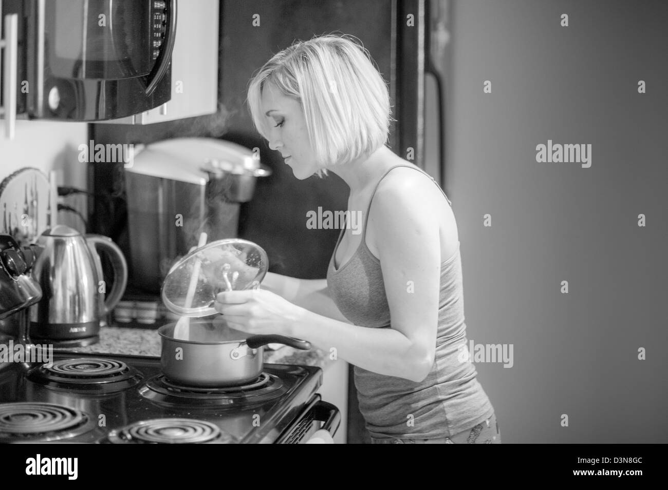 Young blond woman cooking in kitchen Stock Photo - Alamy