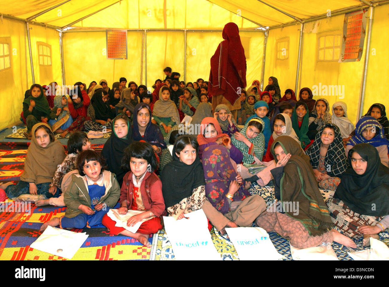 School girls sit in a UNICEF sponsored school tent listening to their ...