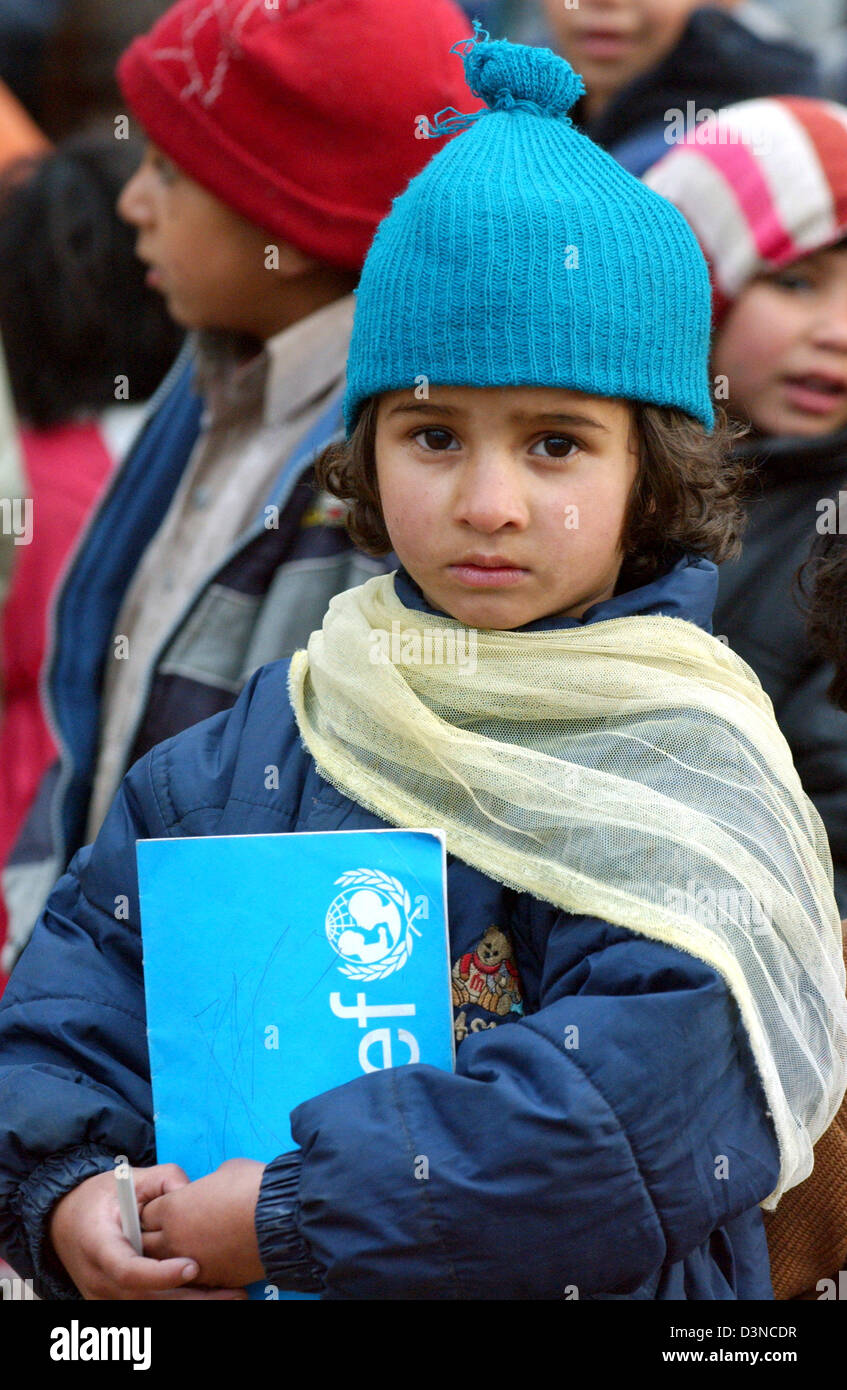 A little girl with a blue knitted hat holds a folder with the logo of ...
