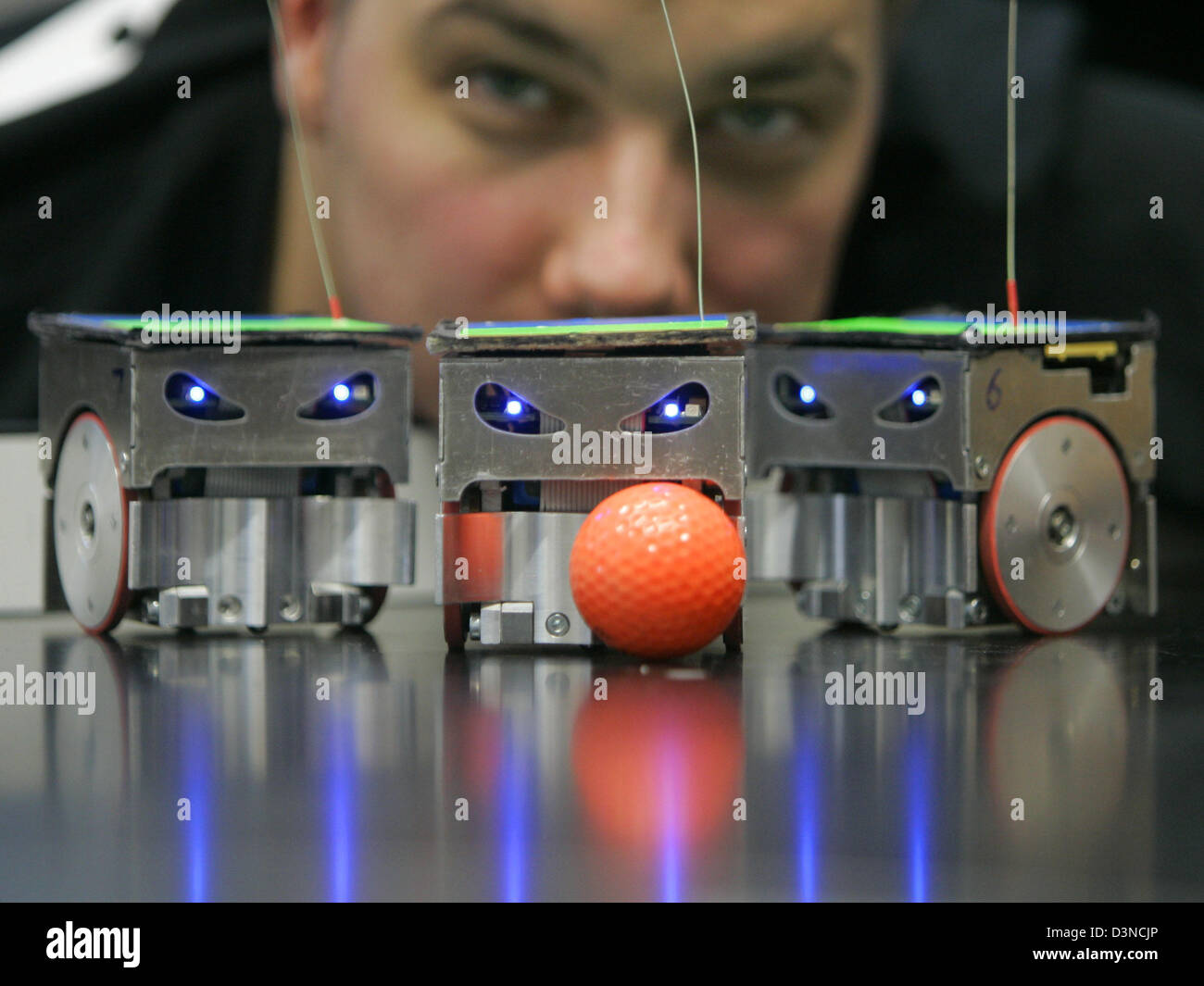 Informatics student Marco Wickrath looks at three MiroSot soccer robots ...