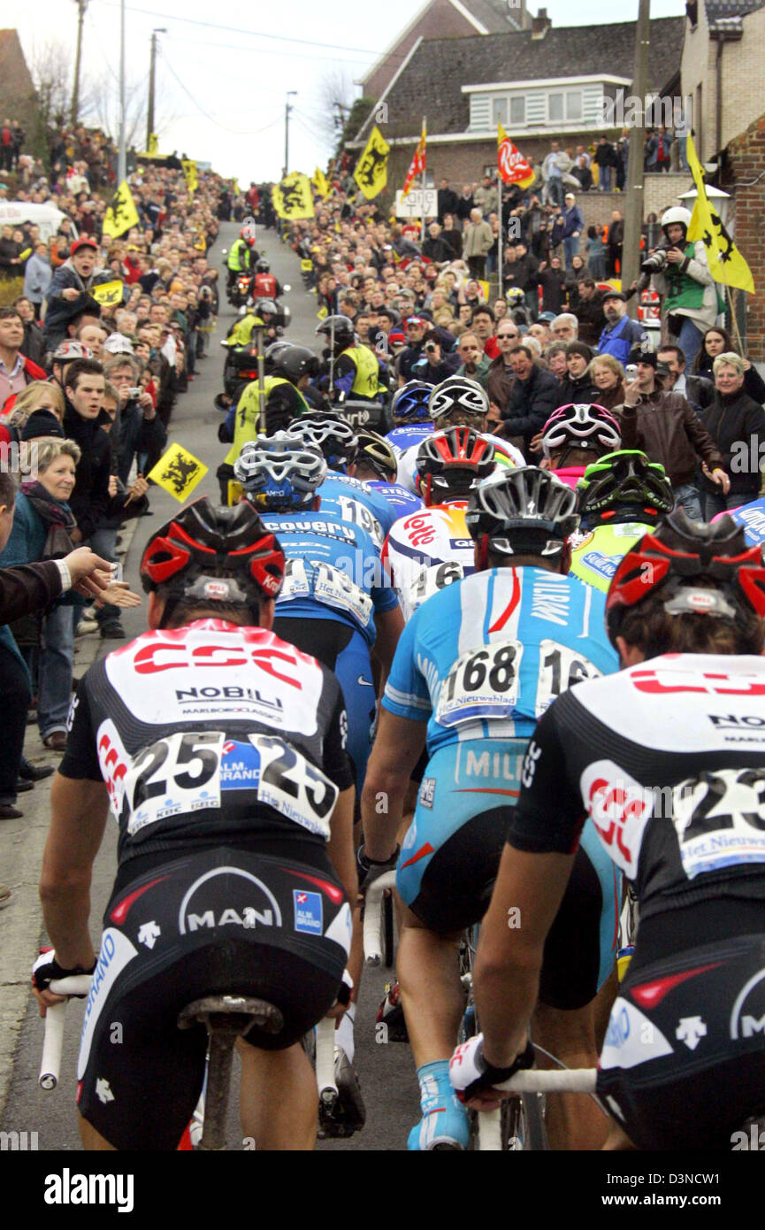 The cyclists ride uphill passing a cheering crowd of spectators at ...