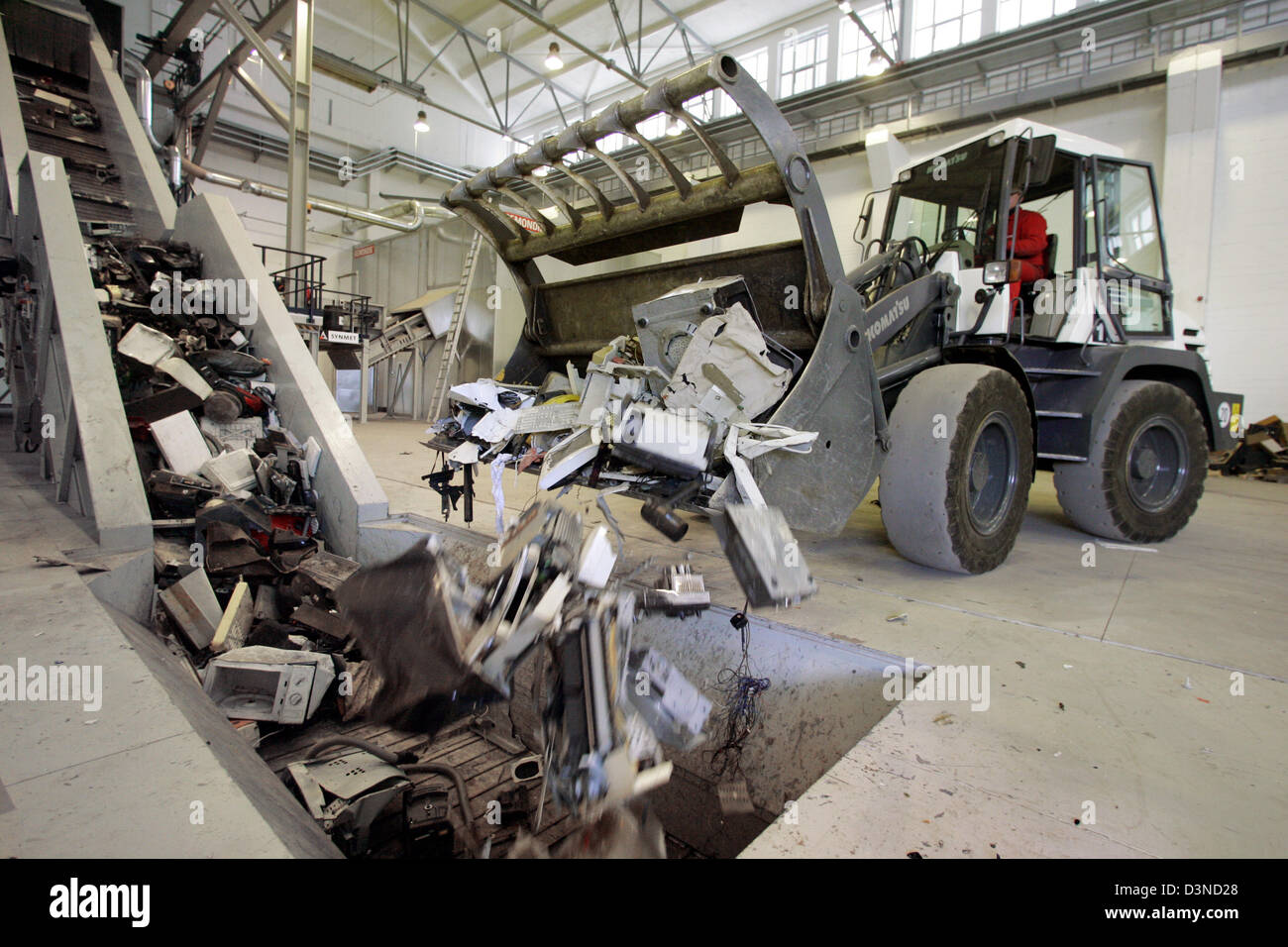 A digger pours electronic junk on a conveyor in the centre for electric ...