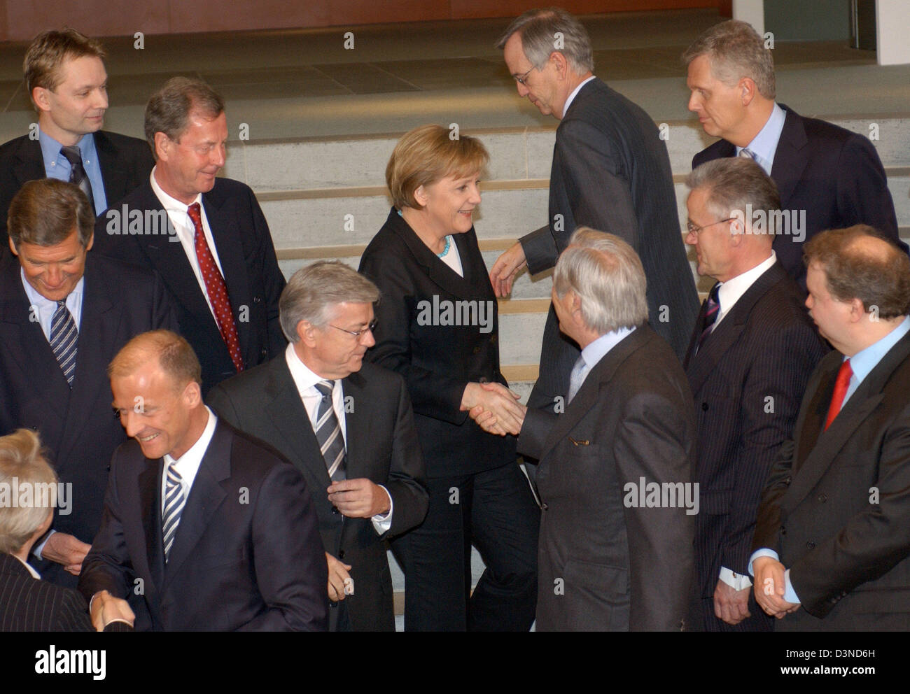 German Chancellor Angela Merkel (C) shakes hands with a representative ...