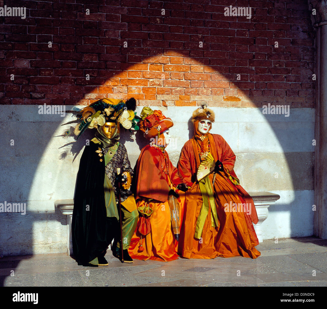 Three masks dressed up in historical costumes sit on a bench at St Mark ...