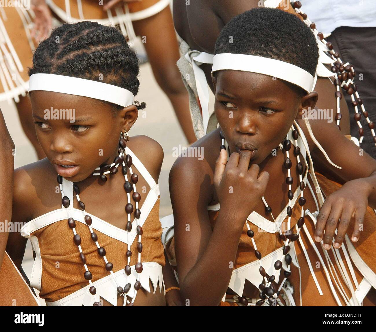 Two children, dressed in traditional clothing, wait for the arrival of ...