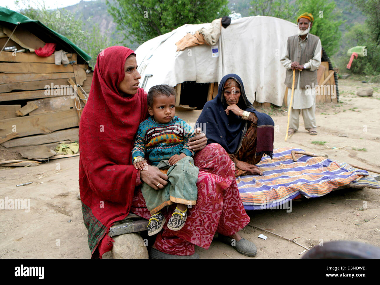 A Pakistani family is pictured in front of their destroyed house during ...