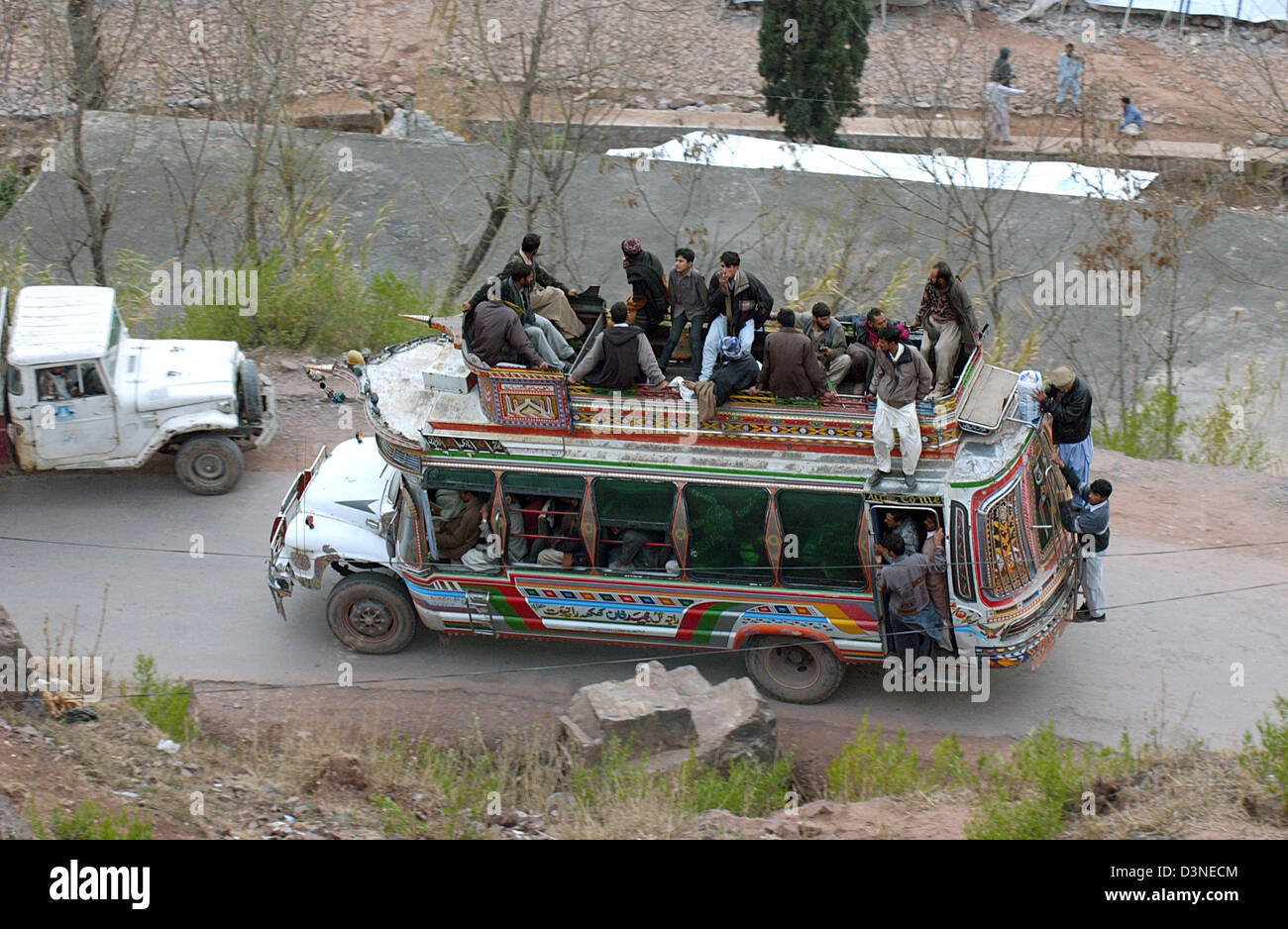 A traditionally painted and crowded bus drives through the destroyed ...