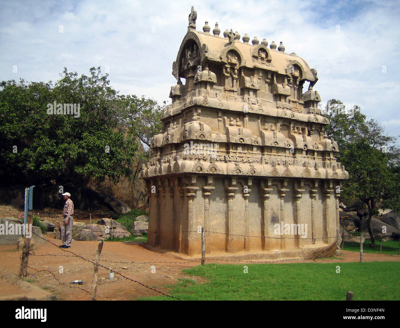 A tourist stands in front of Ganesha Ratha, a rock-temple with carved ...