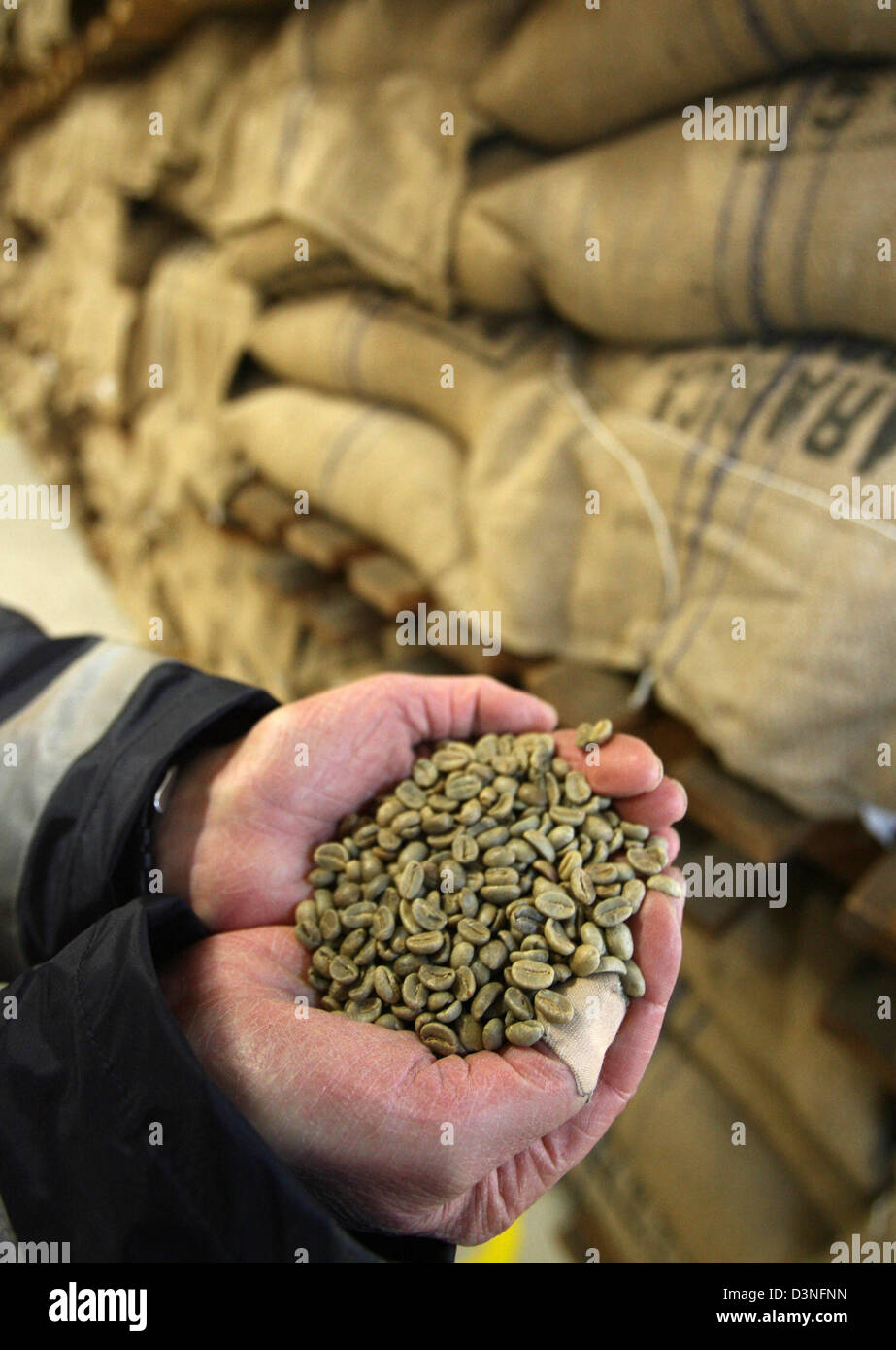 An employee presents a sample of green coffee in Neumann Kaffee Group's ...