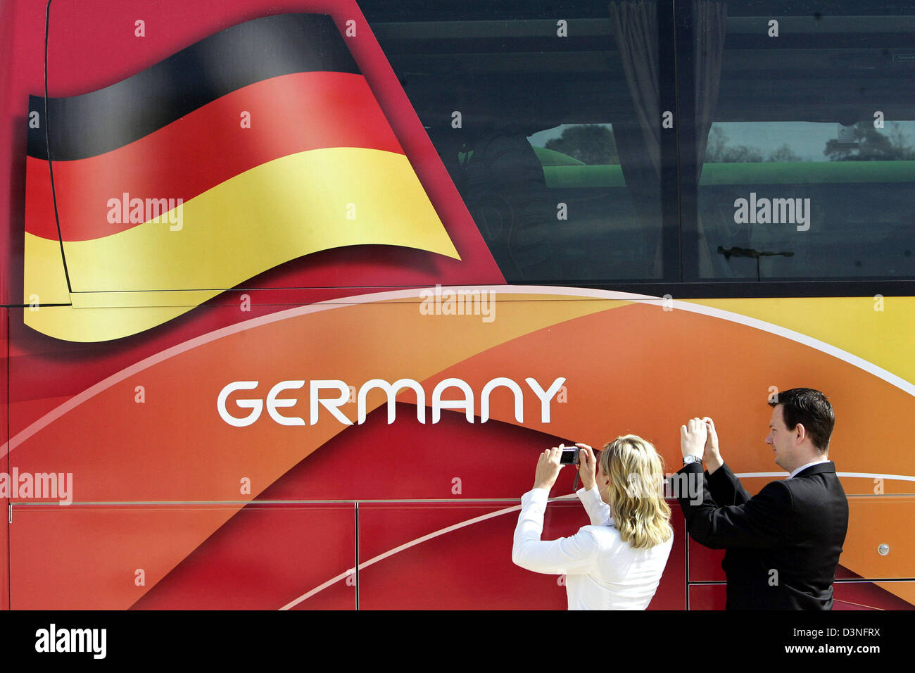 Two soccer fans picture one of the 32 team buses to the FIFA World Cup ...