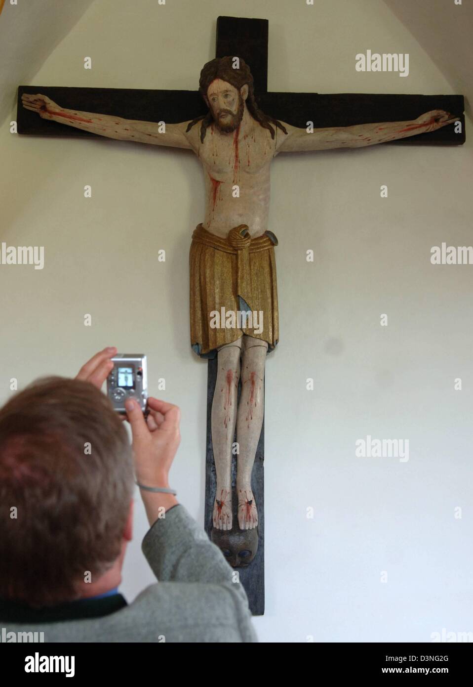 A man takes a picture of the oldest livesize crucifix in Enghausen ...