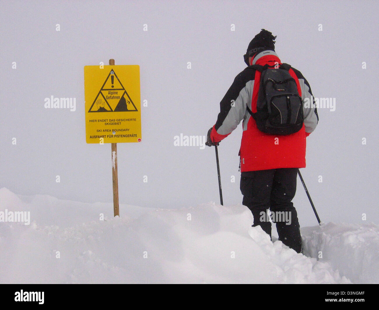 Alpine dangers: A skier rides past a warning sign during poor ...