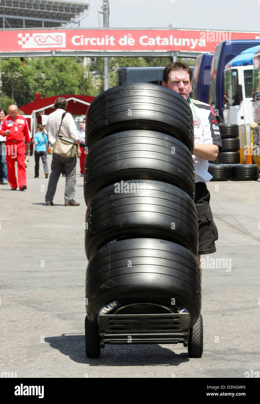 A mechanic of a Formula One team pushes a trolley with tires through ...