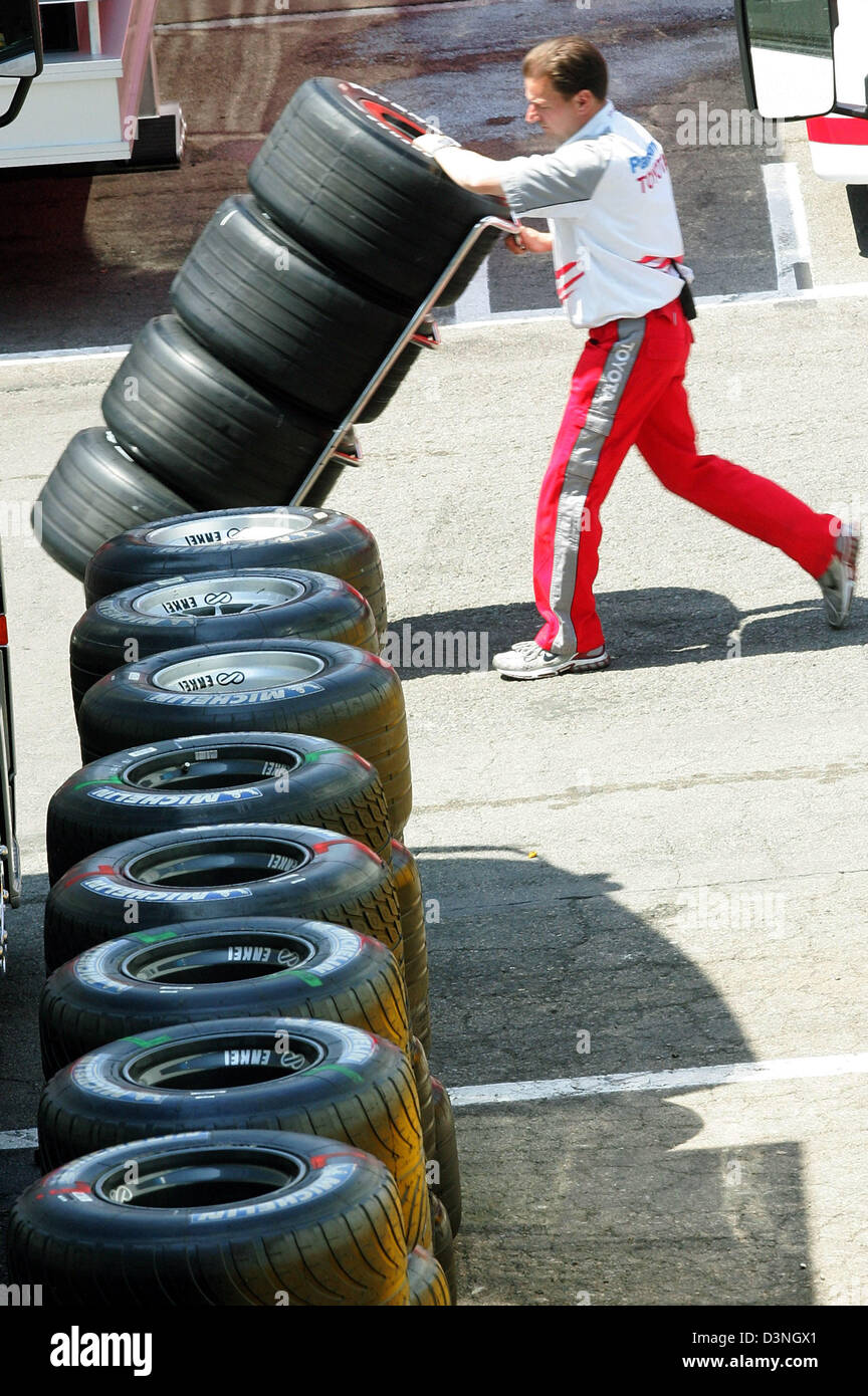 A mechanic pushes a trolley with tyres through the paddock at the ...