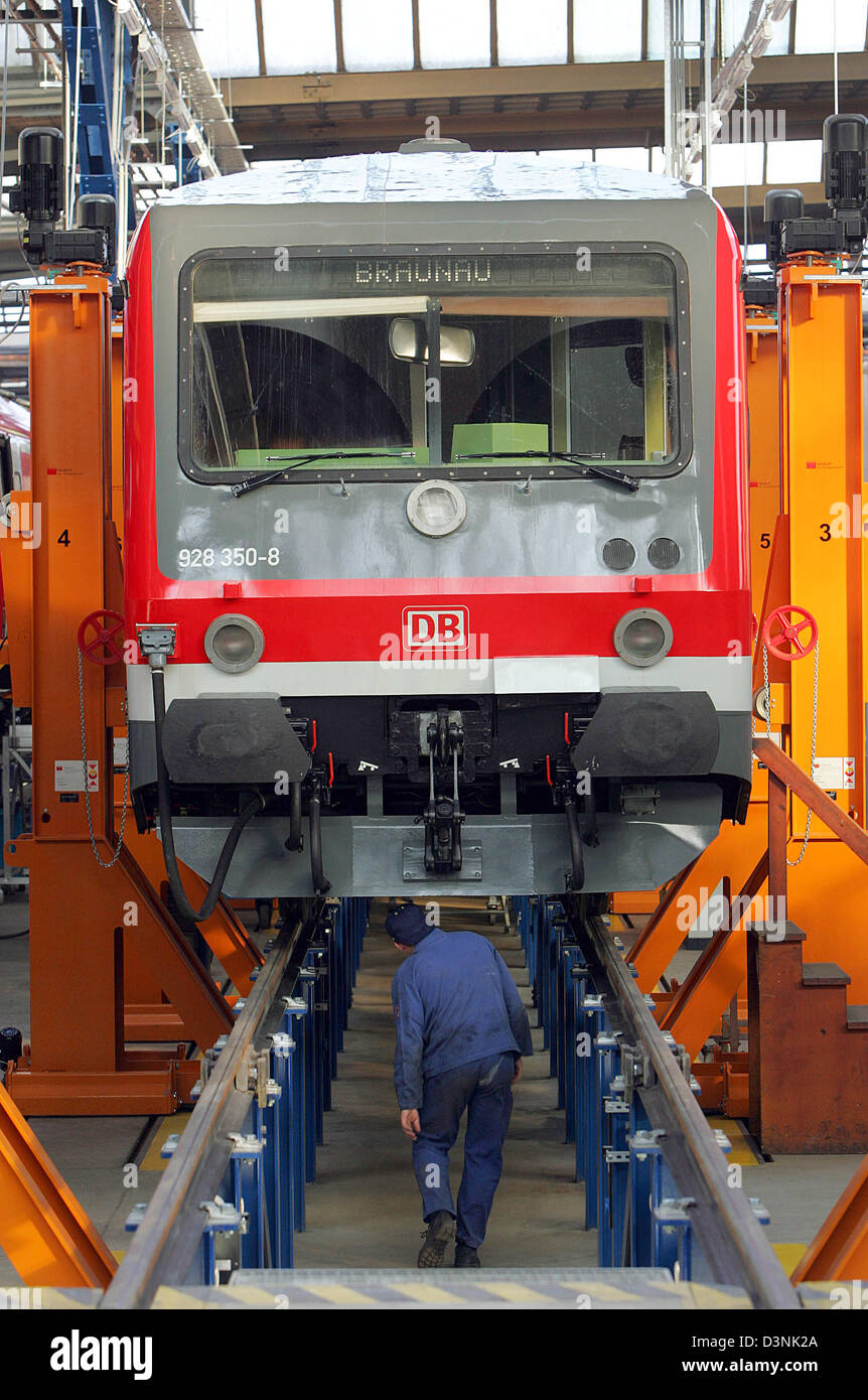 A staff member of the Deutsche Bahn pictured under a diesel multiple ...