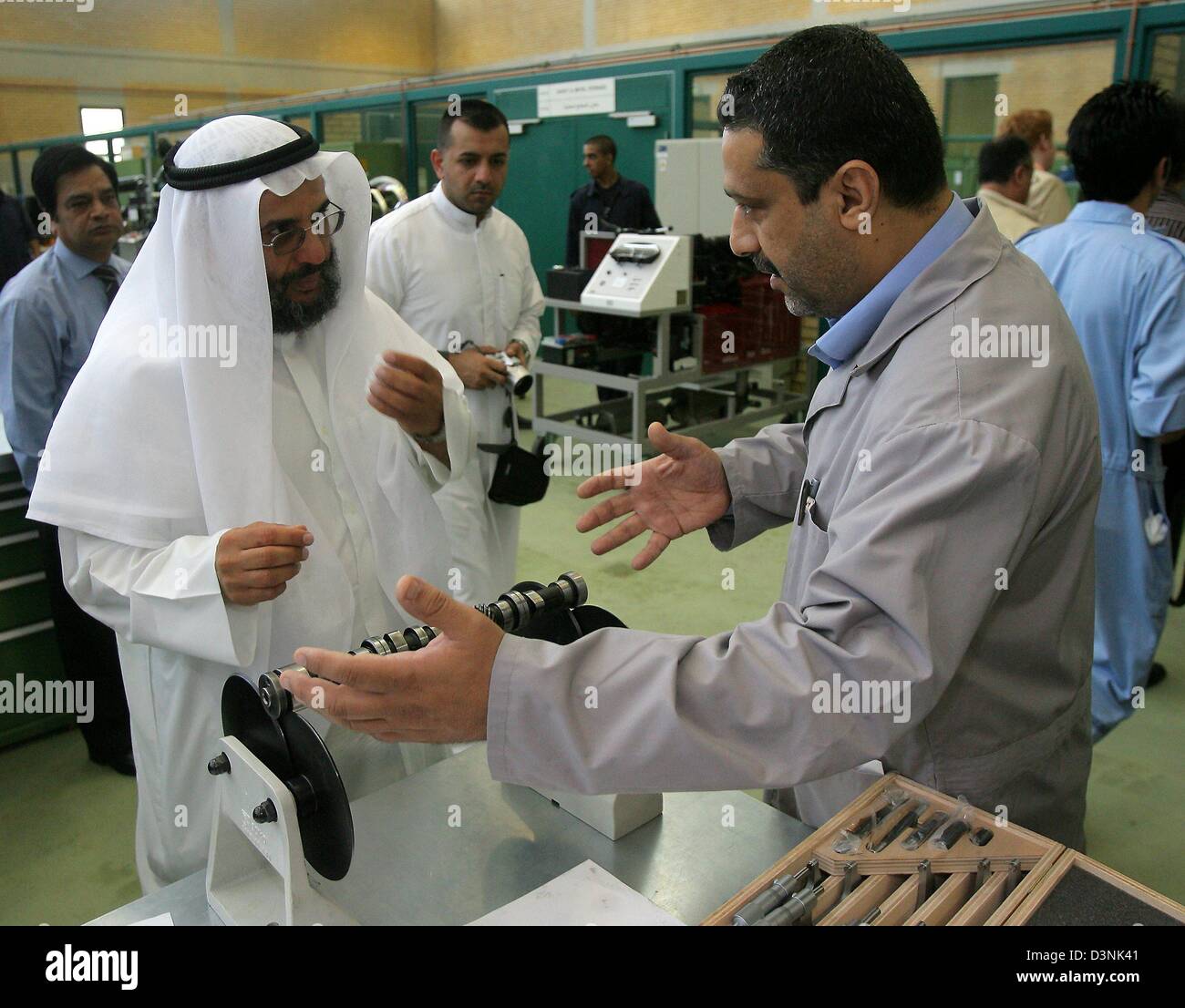 An instructor explains to a man dressed in traditional Arabic clothing ...