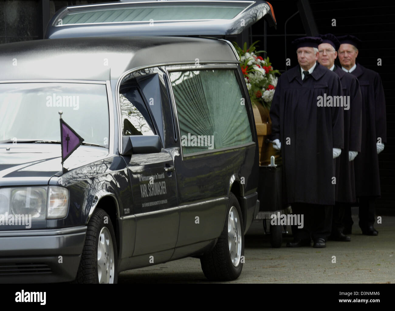 Pallbearers of funeral undertaker Karl Schumacher stand beside a hearse ...
