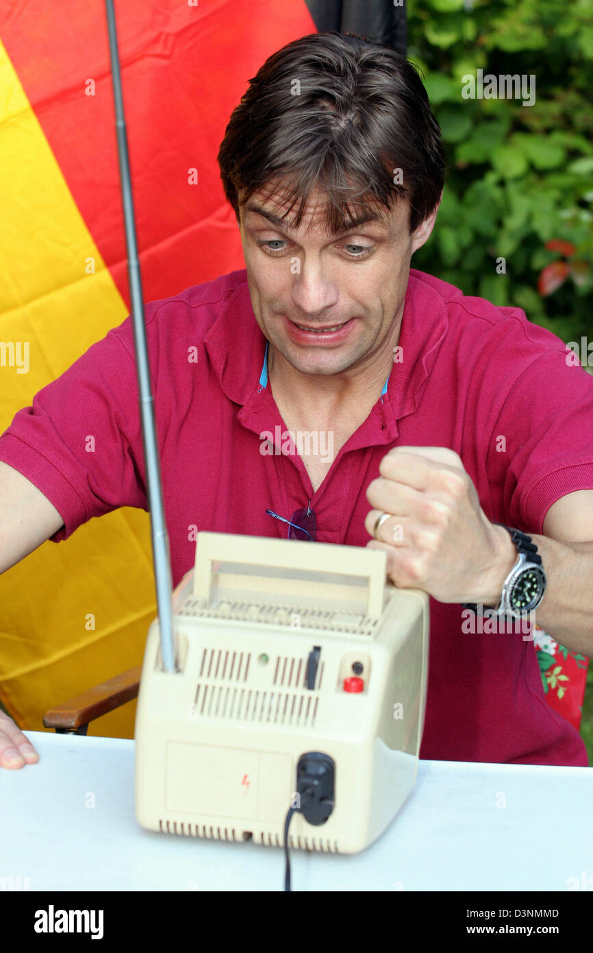 A soccer fan watches a match on a portable TV set at his garden in ...