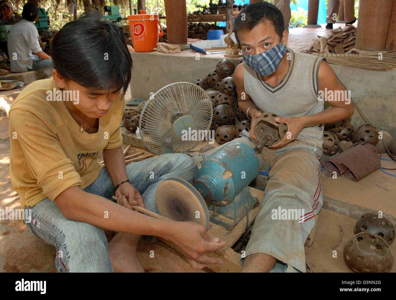 Two young men process coconuts in a small arts and crafts fabric near ...