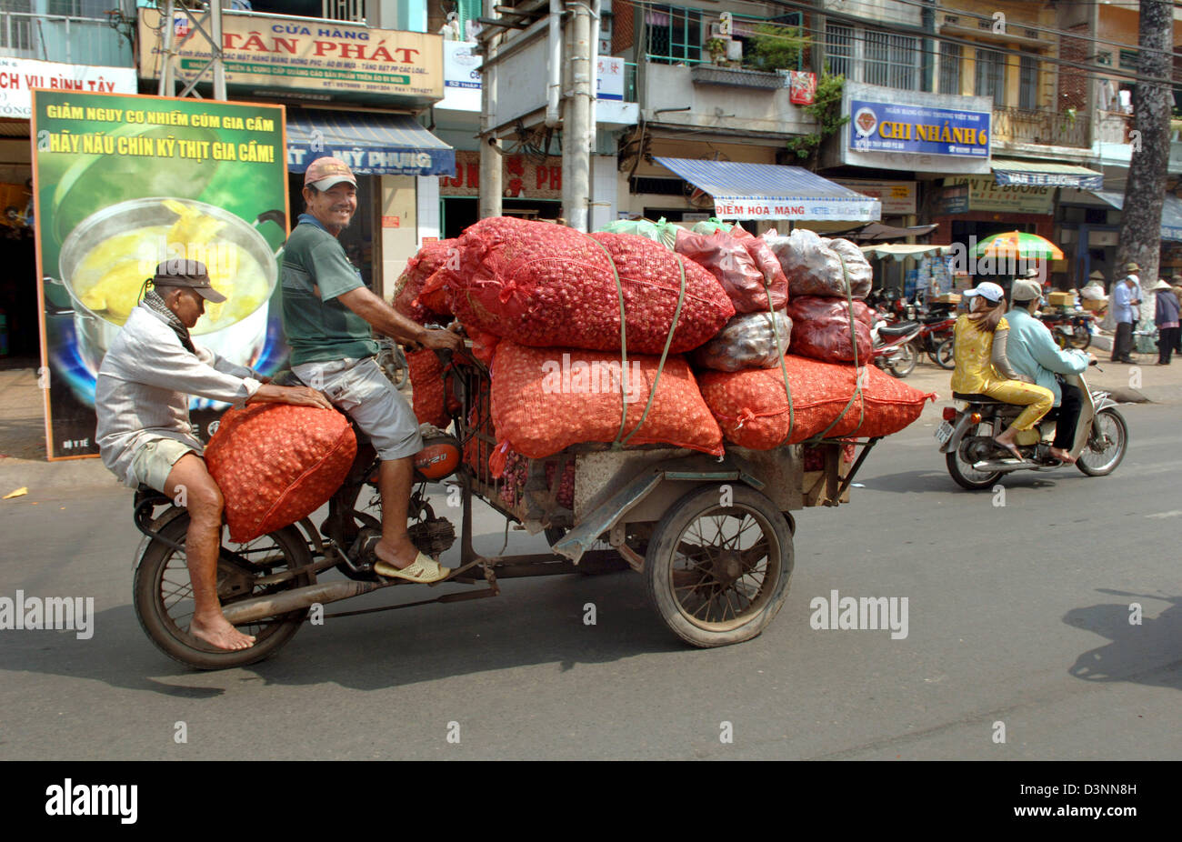 Two men transport big red sacks full of food on their carriage in ...