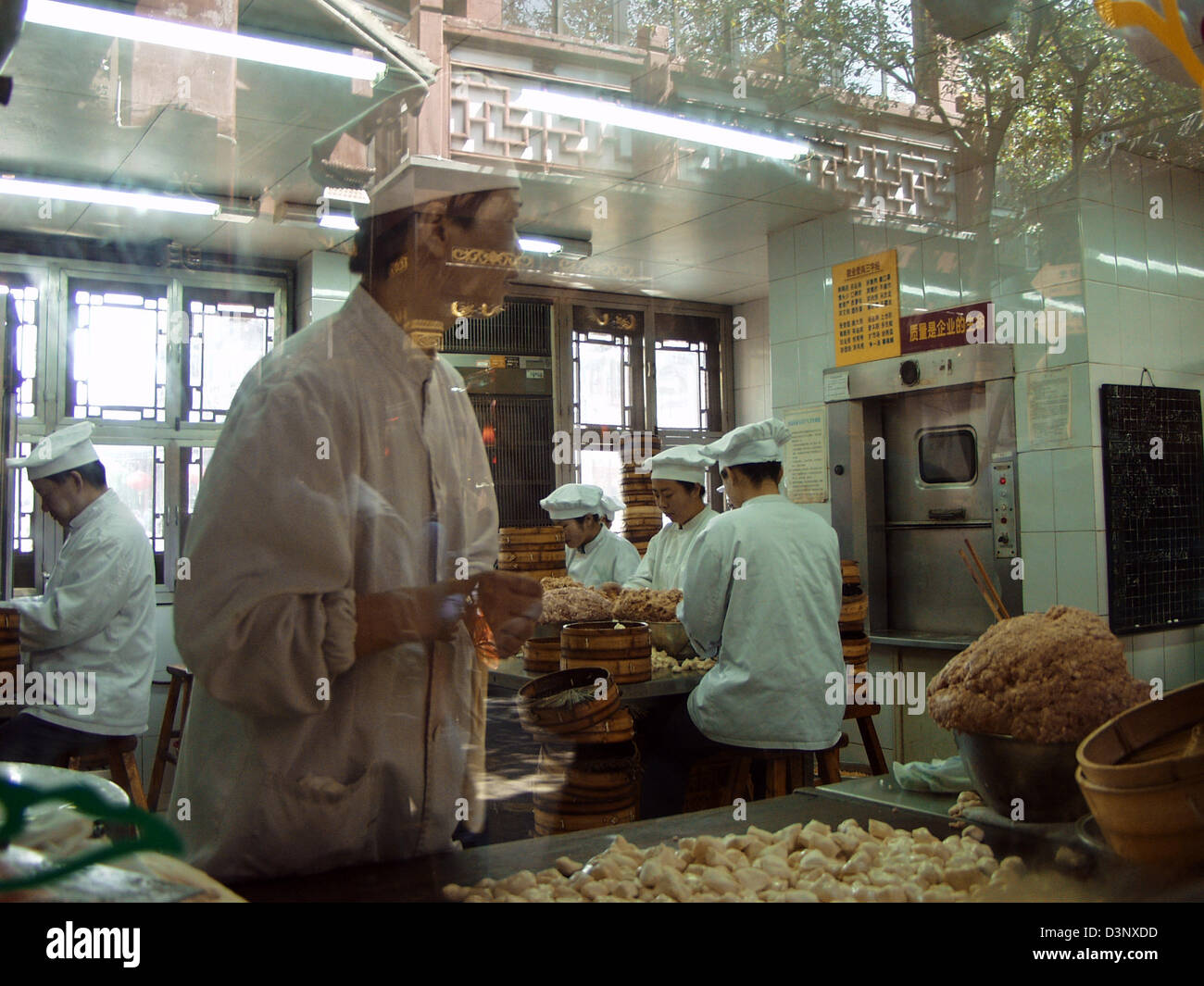 The picture shows a view through a cookshop's window onto five cooks in ...