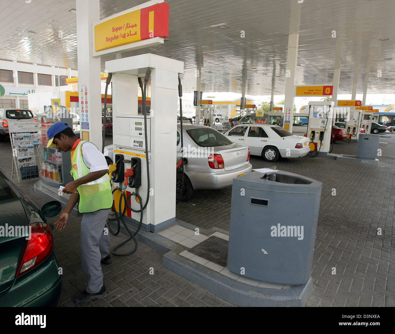 A filling station attendant shuts a fuel tank cap in front of petrol ...
