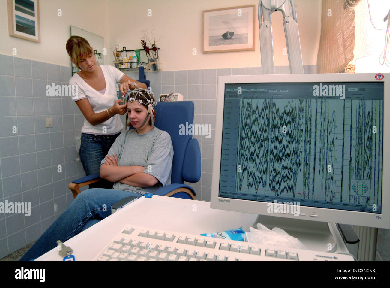 A receptionist prepares a patient for an EEG in a neurologist surgery ...