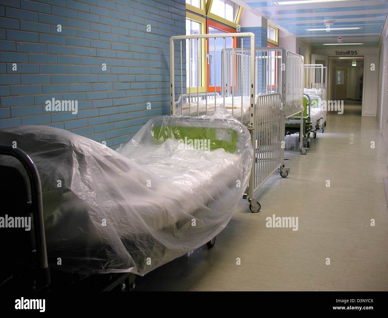 The photo shows a hospital floor with empty beds covered with foil in ...