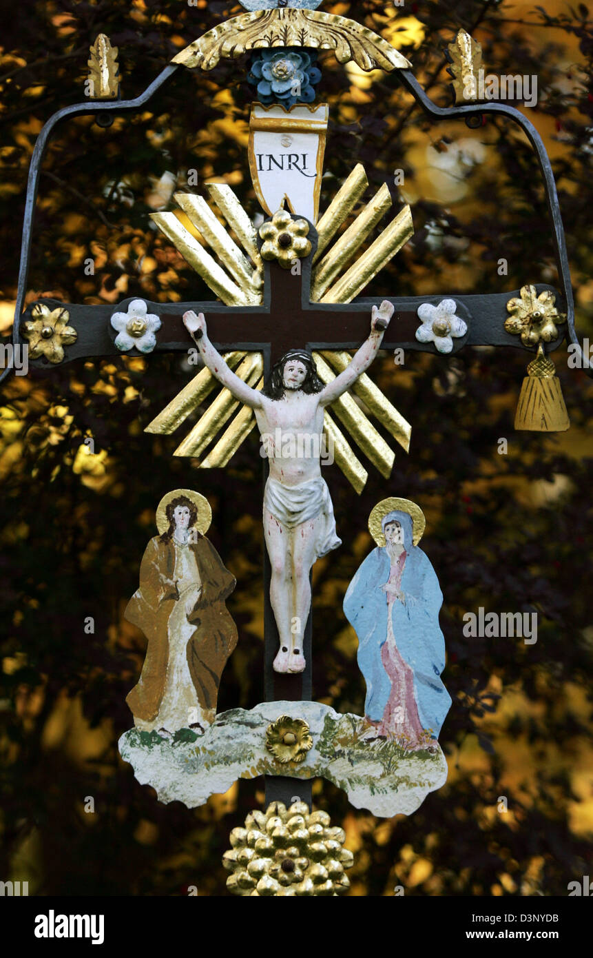 The picture shows a cross ornated with iron, painted bloom, a golden ...