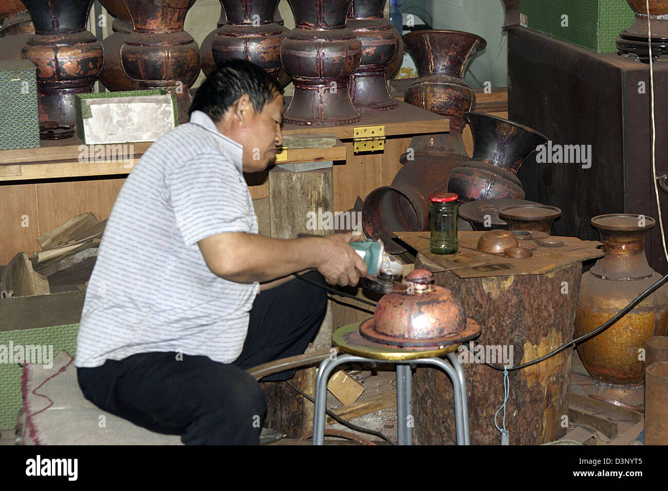 A coppersmith manufactures vases and vessels in a coppersmith's in ...