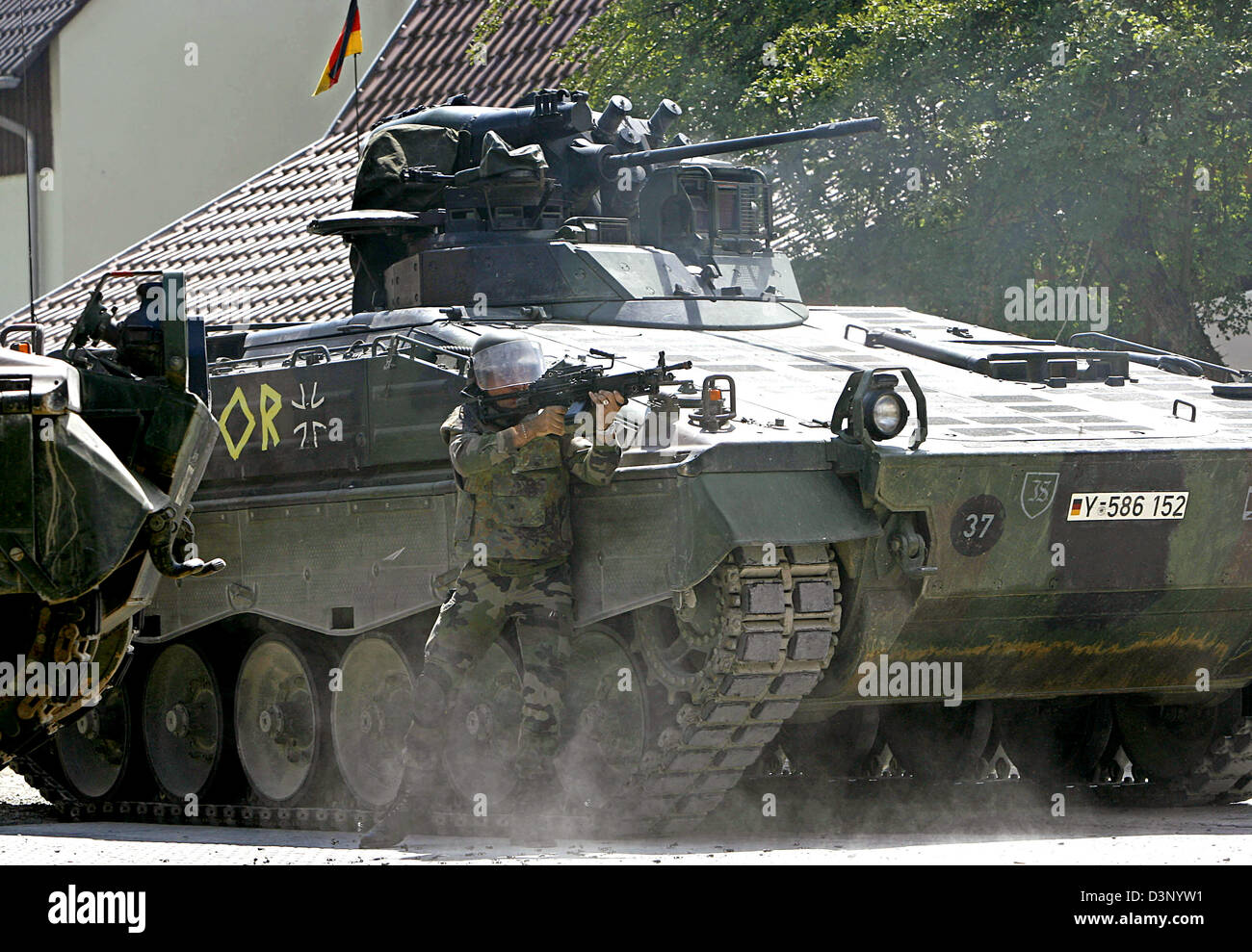 A soldier takes defilade behind a tank and aims in the training village ...