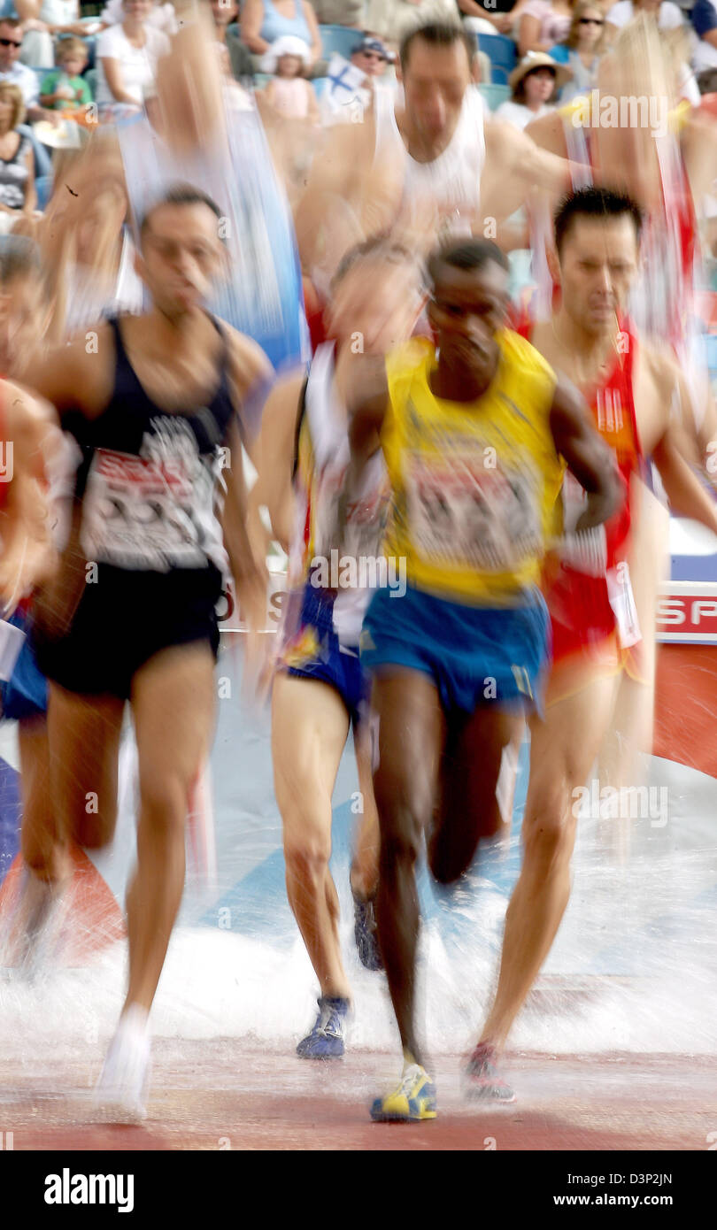 Participants of the men's 3000 metres steeplechase run through a water ...