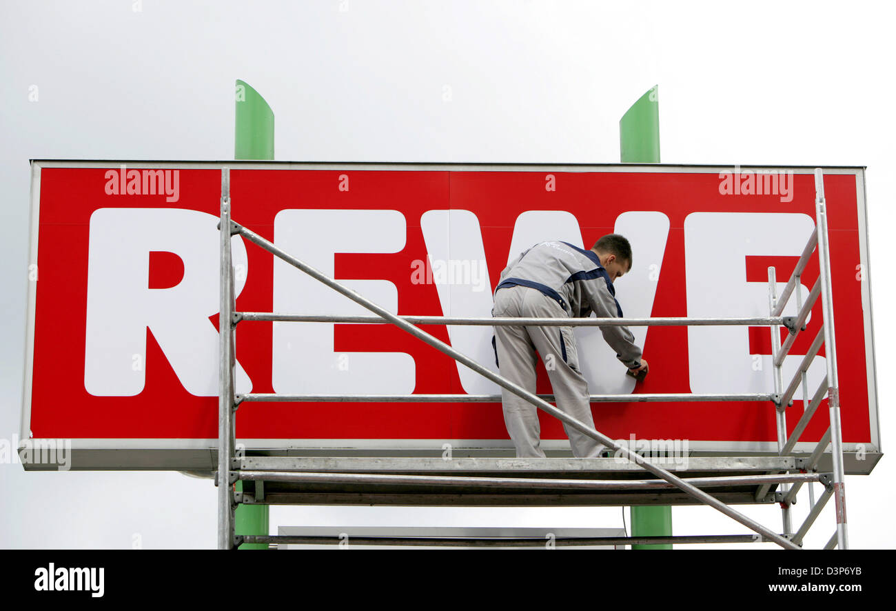 An employee of a labelling company sets up the new Rewe Group logo at ...