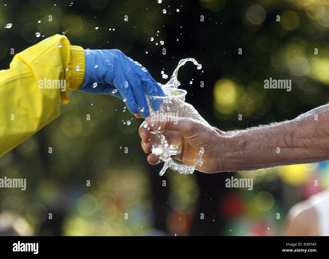 A helper passes a cup with fresh water to a runner during the Marathon ...