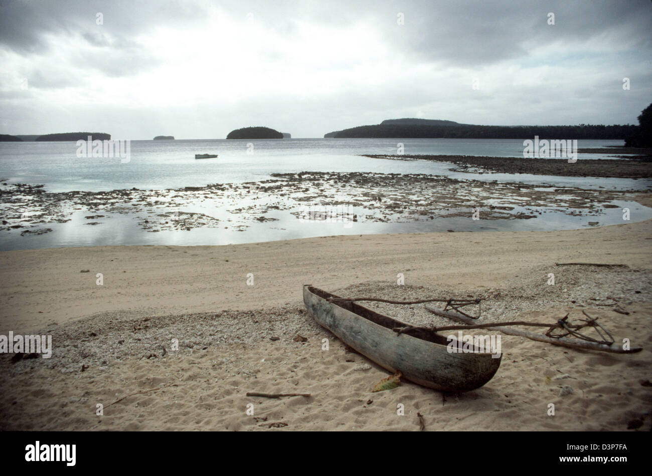 A dugout canoe with an outrigger lies on a deserted beach, Tonga ...