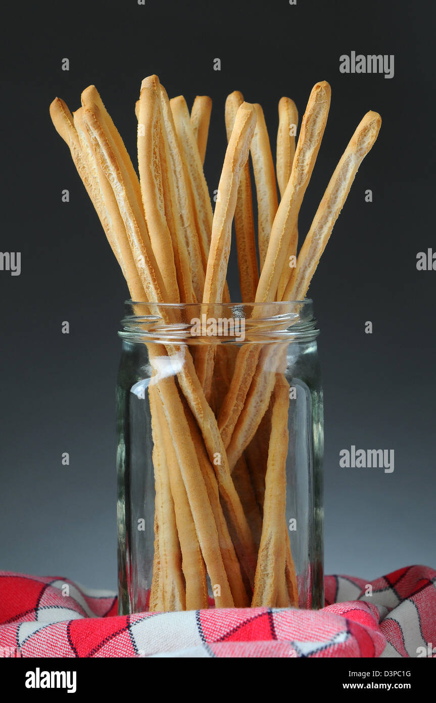 Closeup of a jar full of bread sticks on a checkered napkin with a ...